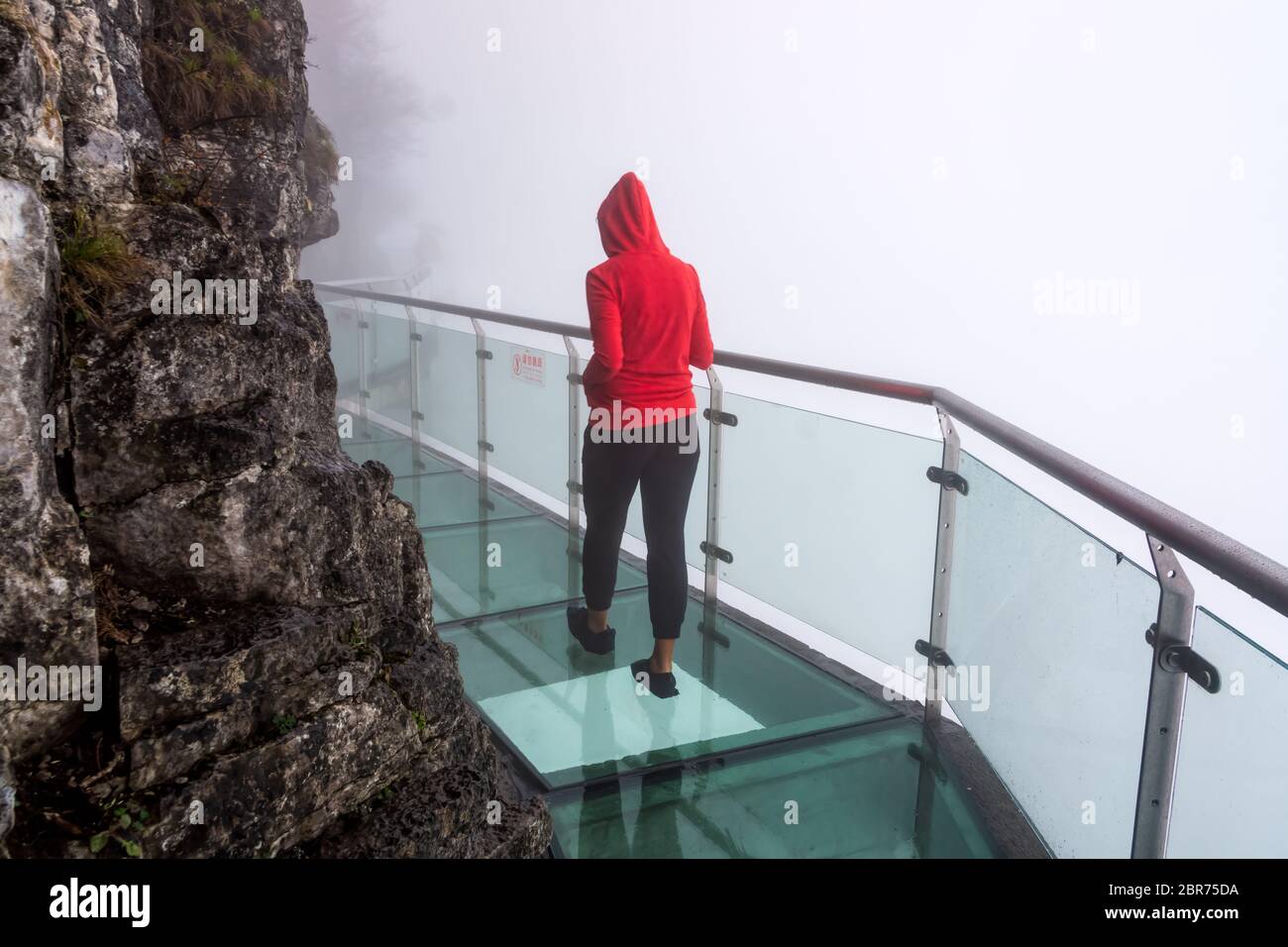 Young woman walking on glass Sky Walk at Tianmen Mountain, path ...