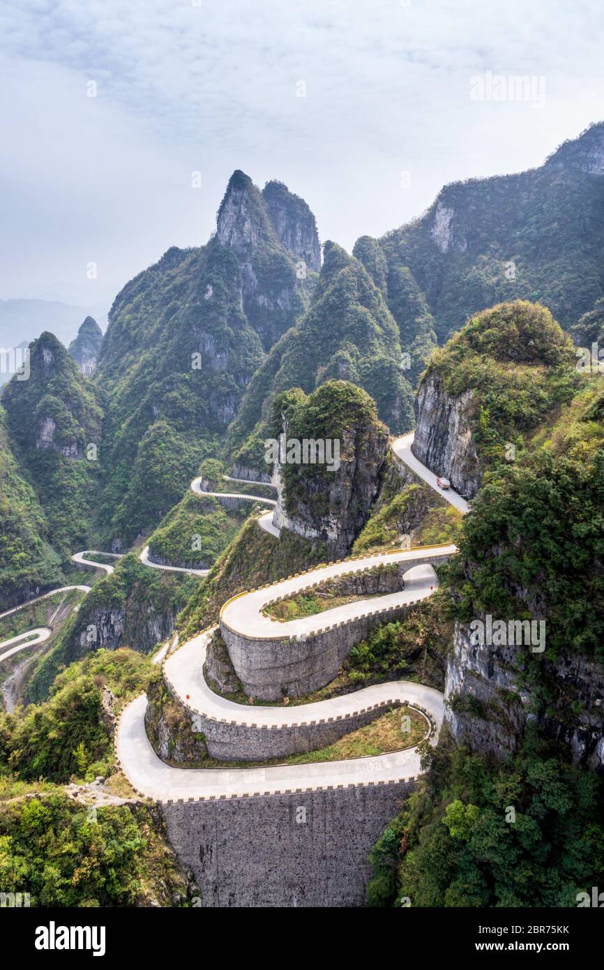 The winding road of Tianmen Mountain with sharp cliffs and green tries ...