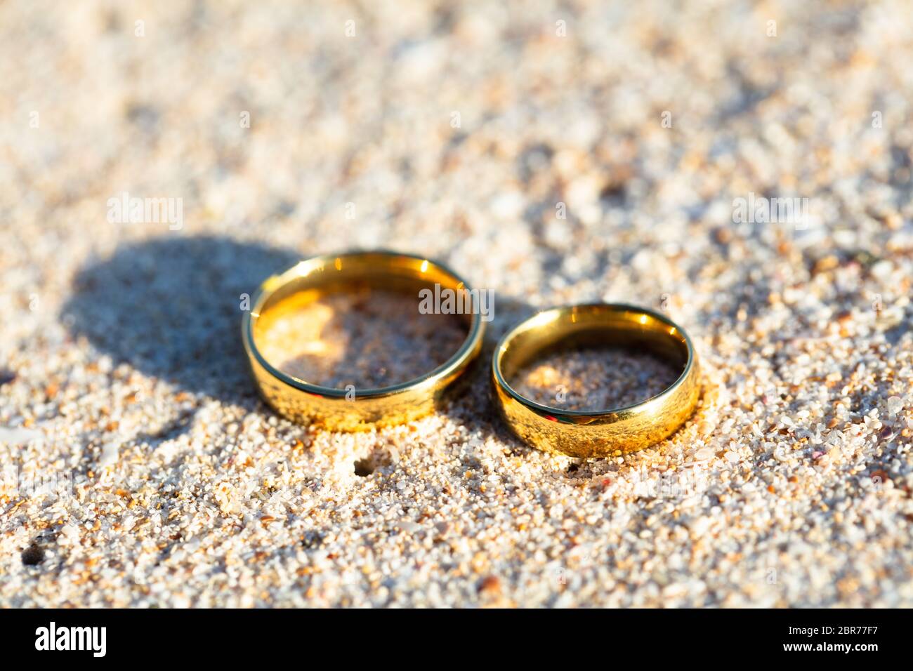 Golden And Shiny Wedding Rings On Sand At Beach Stock Photo - Alamy