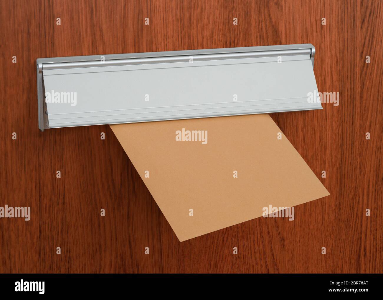 An unlabeled brown envelope in a letterbox Stock Photo - Alamy