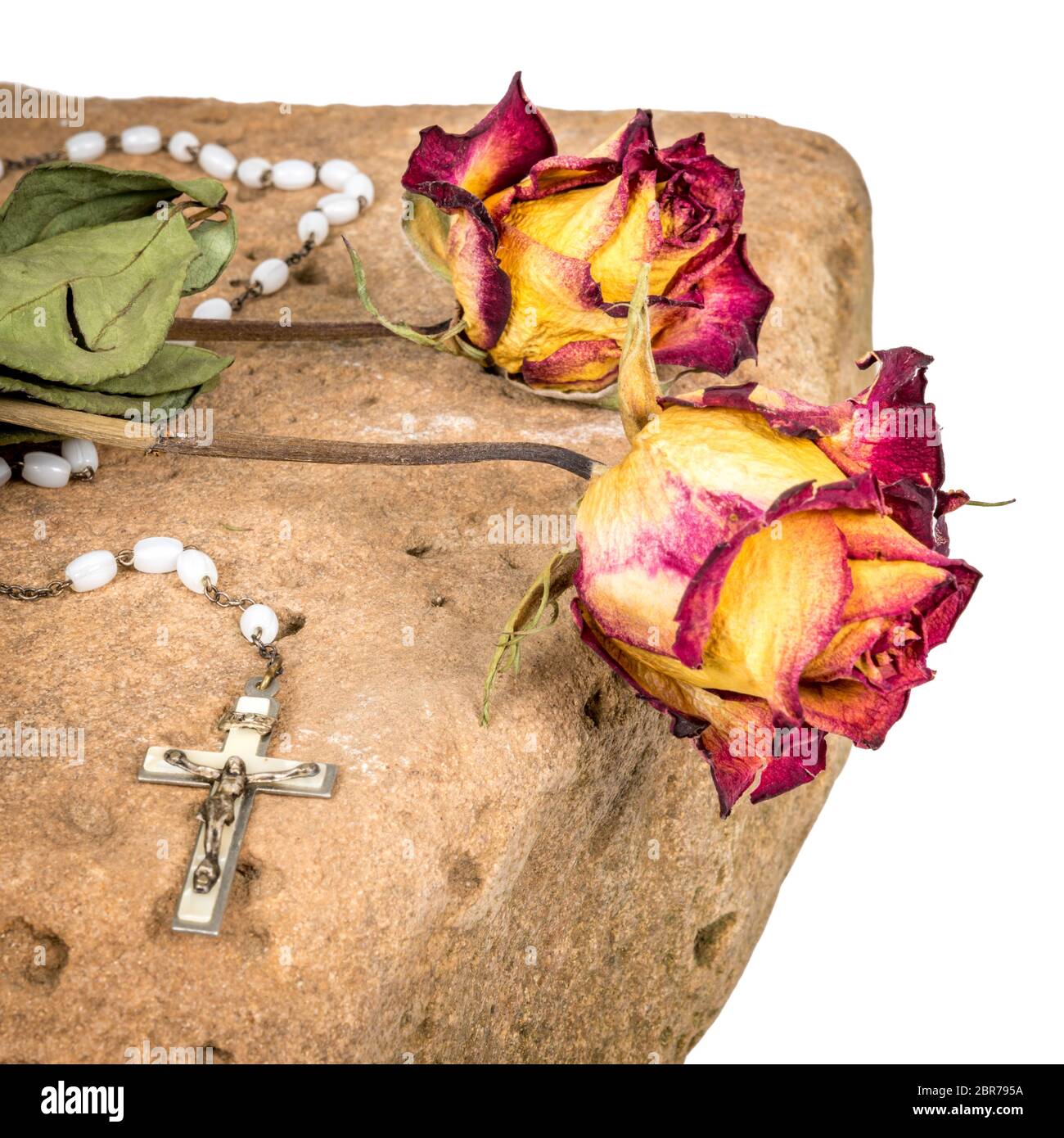 Christian cross on rosary and a dry yellow red roses lie on a red ...