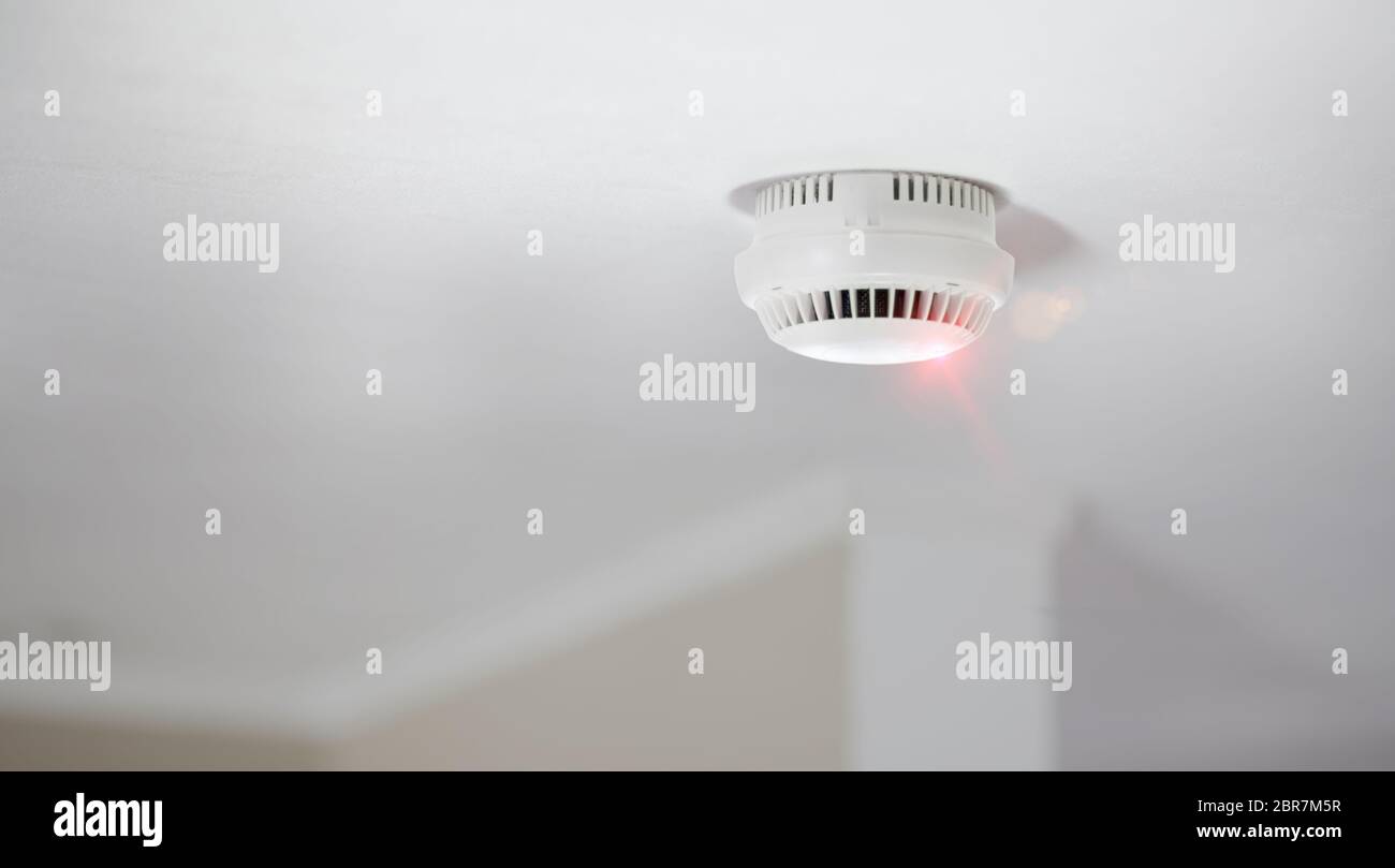 Smoke detector mounted on roof in apartment Stock Photo - Alamy