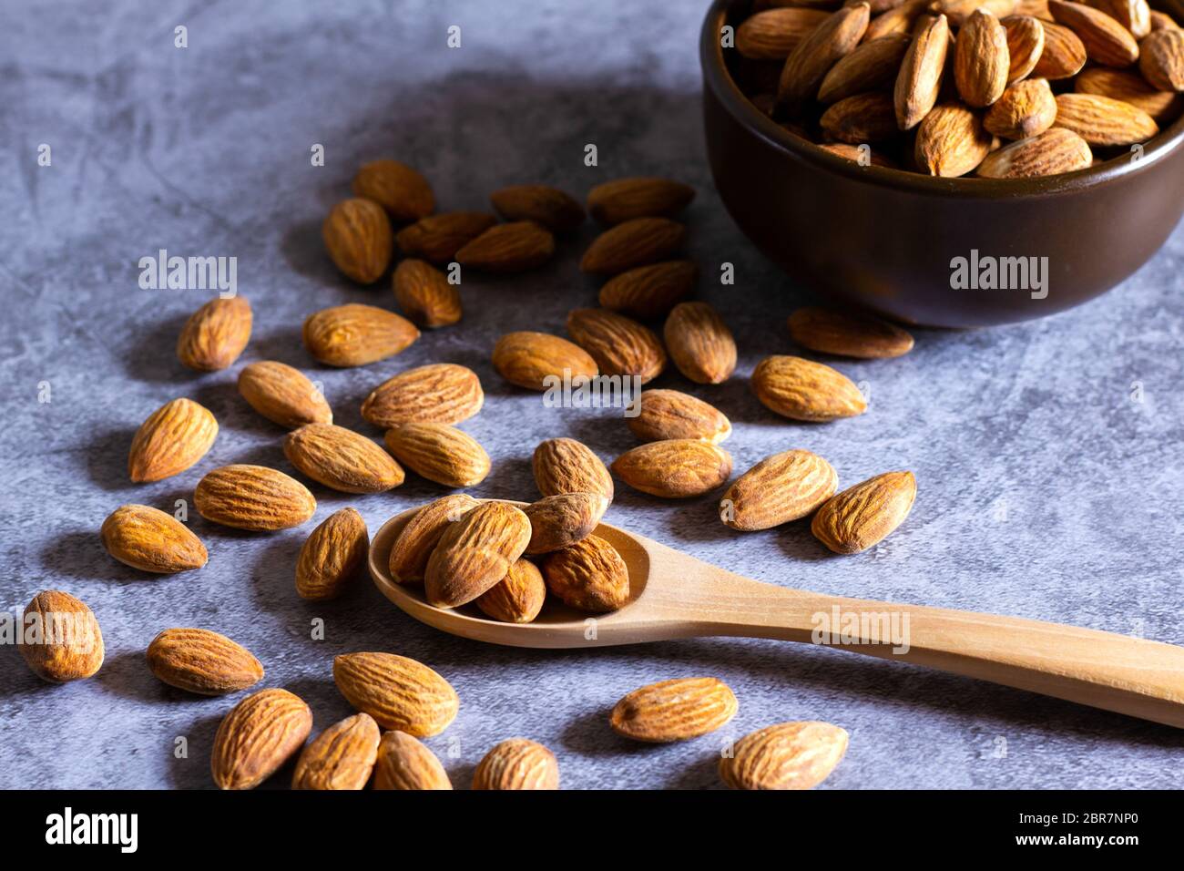 Almonds with wooden bowl and spoon on the dark table Stock Photo - Alamy