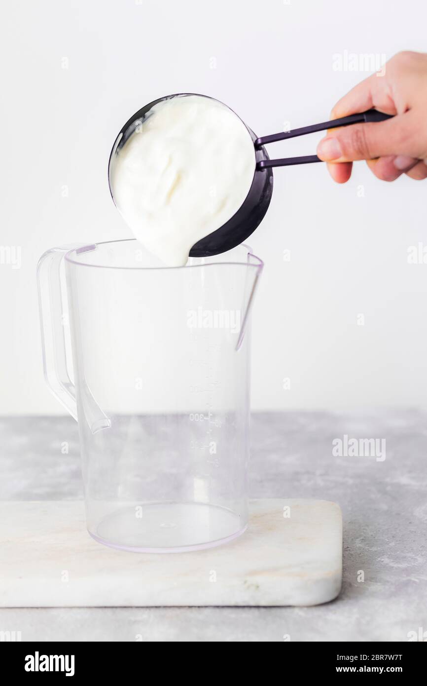 Lady pouring Yogurt in a Jug for Mango Lassi Stock Photo - Alamy