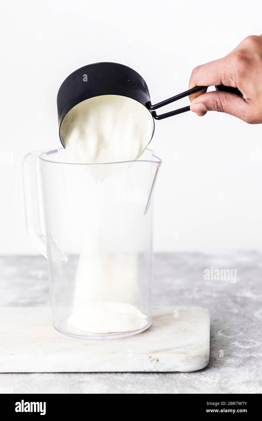Lady pouring Yogurt in a Jug for Mango Lassi Stock Photo - Alamy