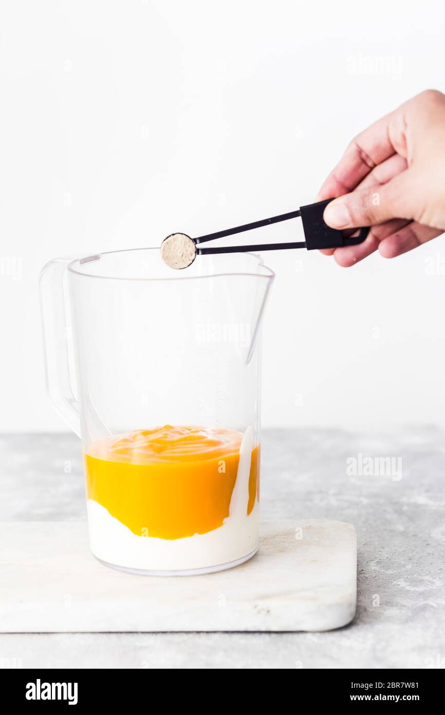 Lady adding cardamom powder to the jug for mango lassi Stock Photo - Alamy
