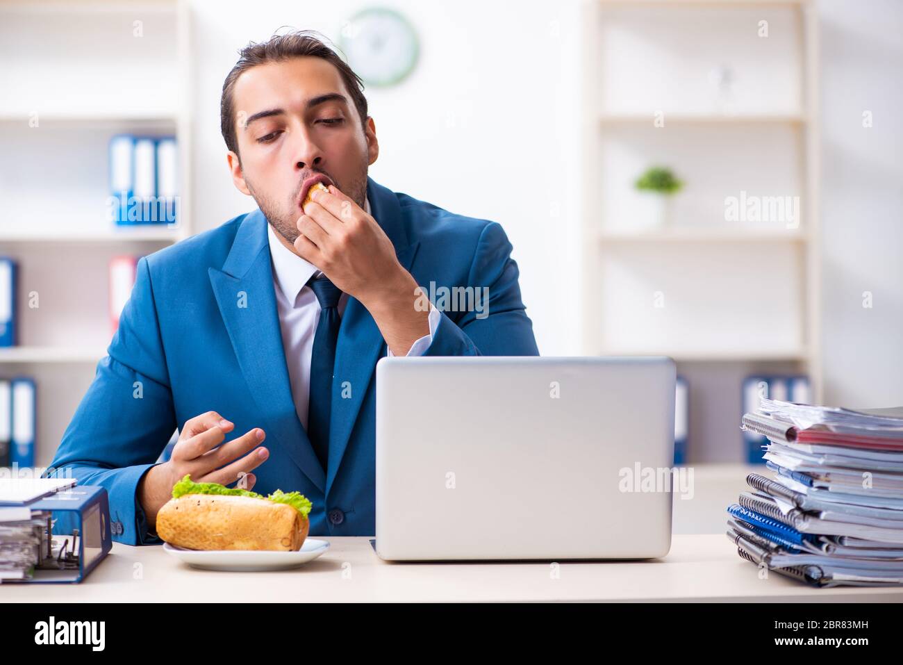 Young employee having breakfast at workplace Stock Photo - Alamy