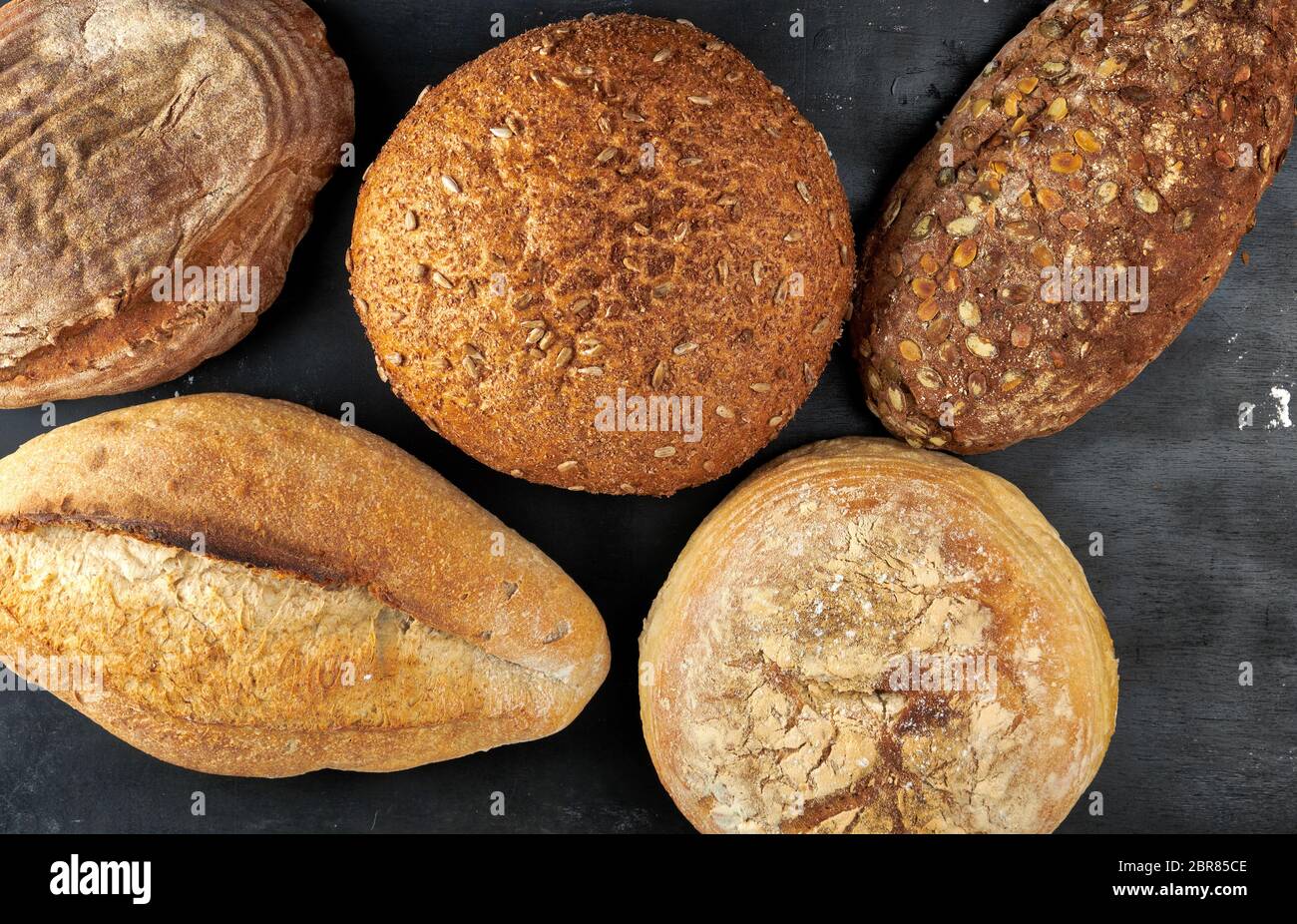 baked various loaves of bread on a black background, top view Stock ...