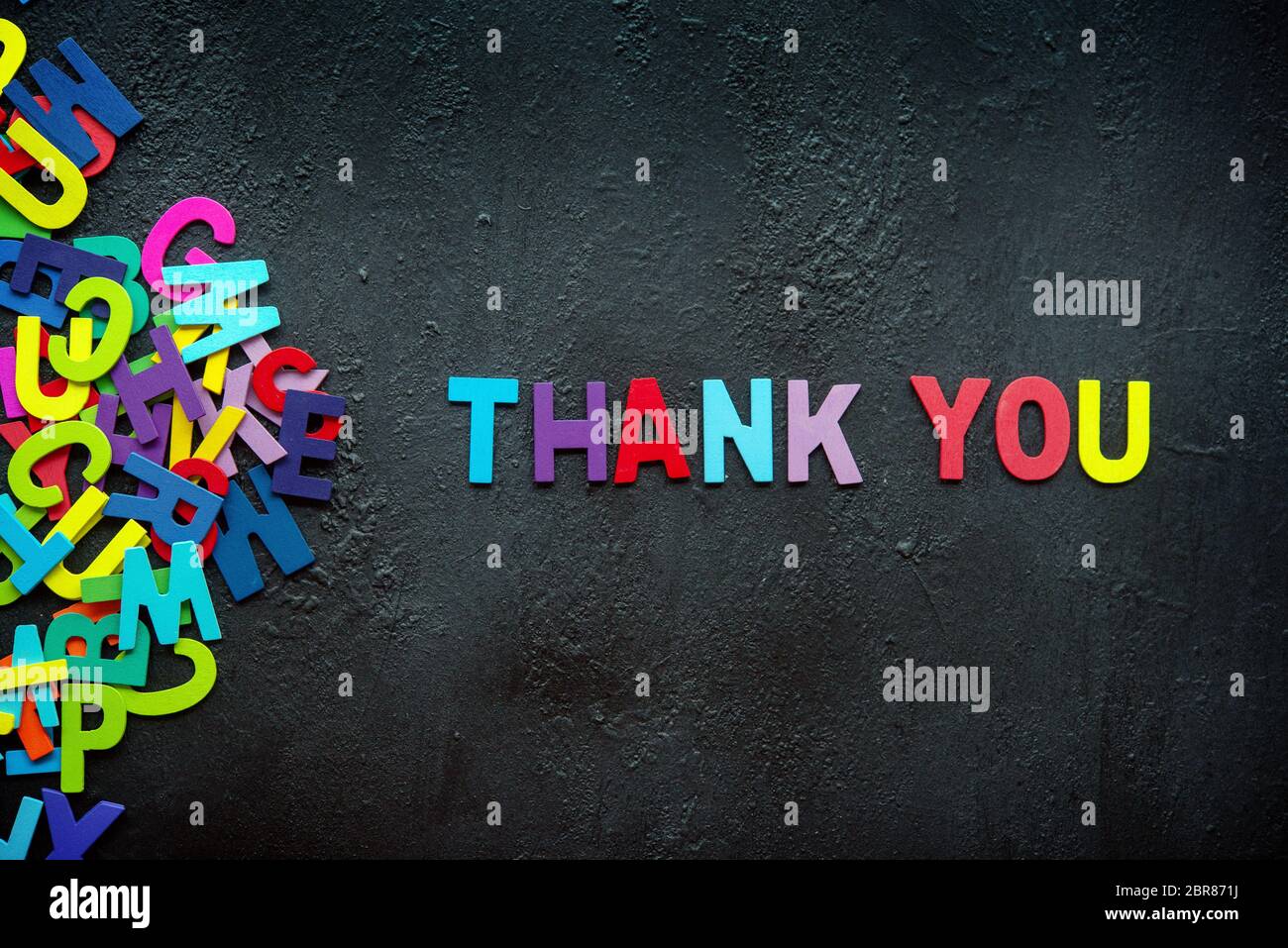 The colorful words "THANK YOU" made with wooden letters next to a pile ...