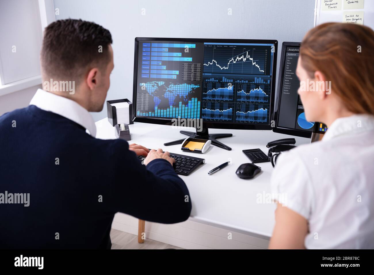 Side View Of Two Businesspeople Examining Graph On Computer At ...