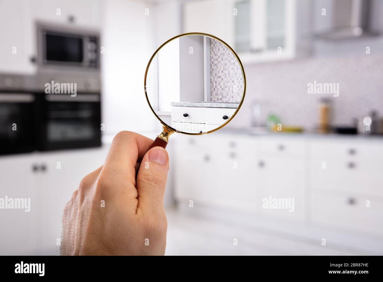 Close-up Of A Man's Hand Holding Magnifying Glass Over The Kitchen In ...