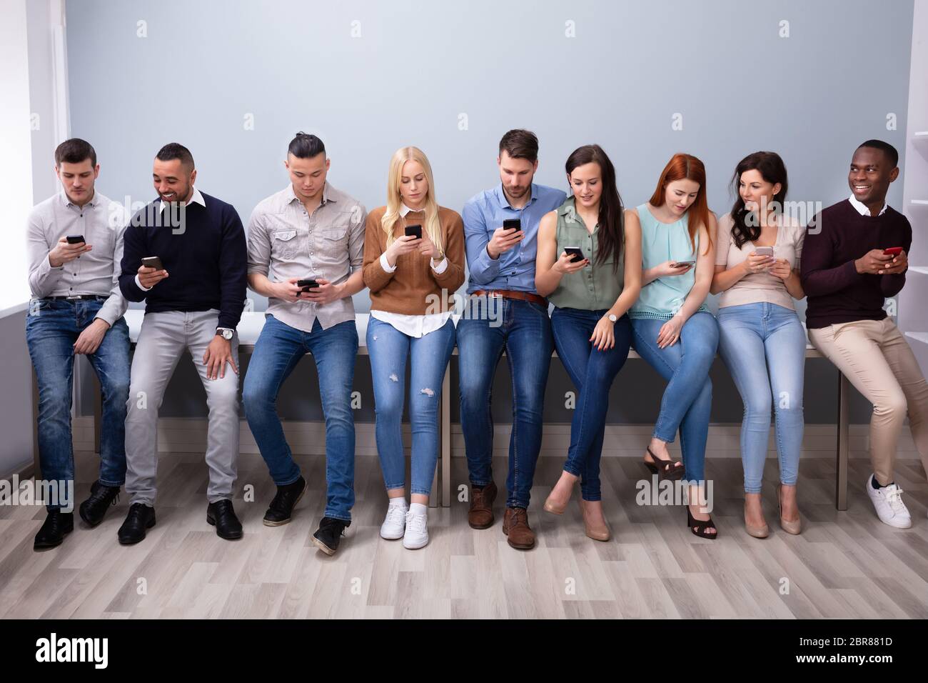 Multi-ethnic Young People Leaning Near Table In Row Using Smartphone Stock Photo - Alamy