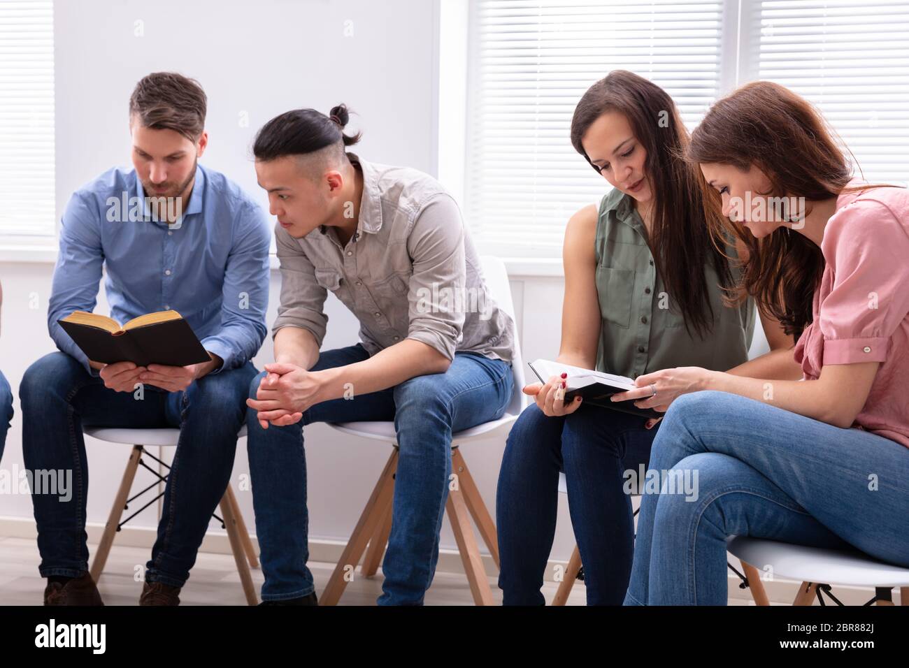 Group Of Friend Sitting Together On Chair Reading Bible Stock Photo - Alamy