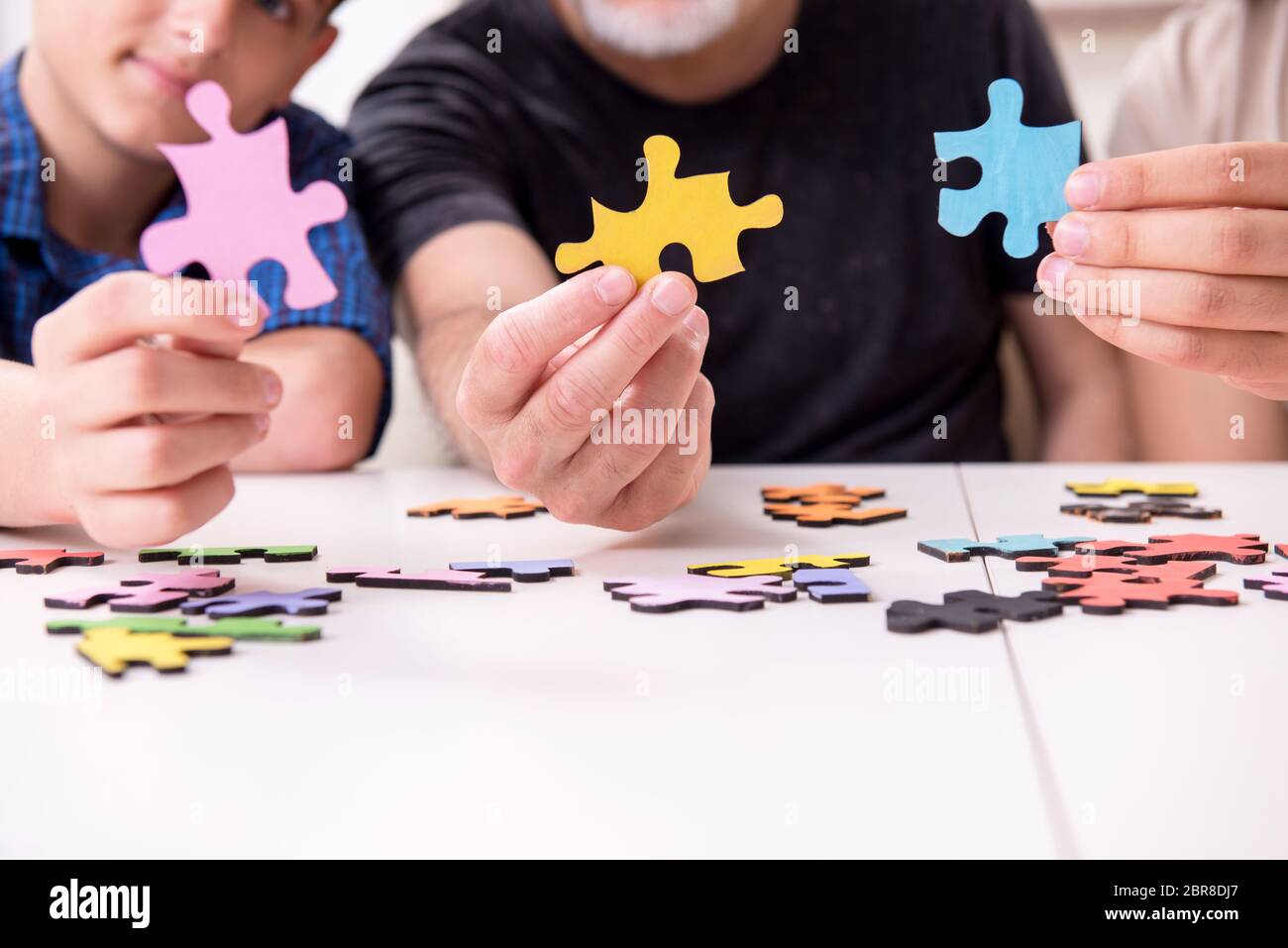 Three generations of family playing jigsaw puzzle Stock Photo - Alamy