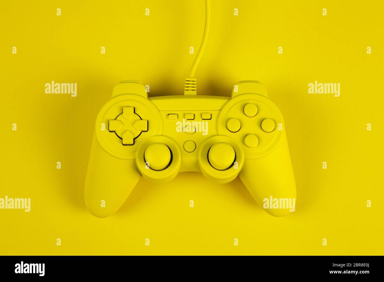 a yellow painted video game controller on a plain background of the ...