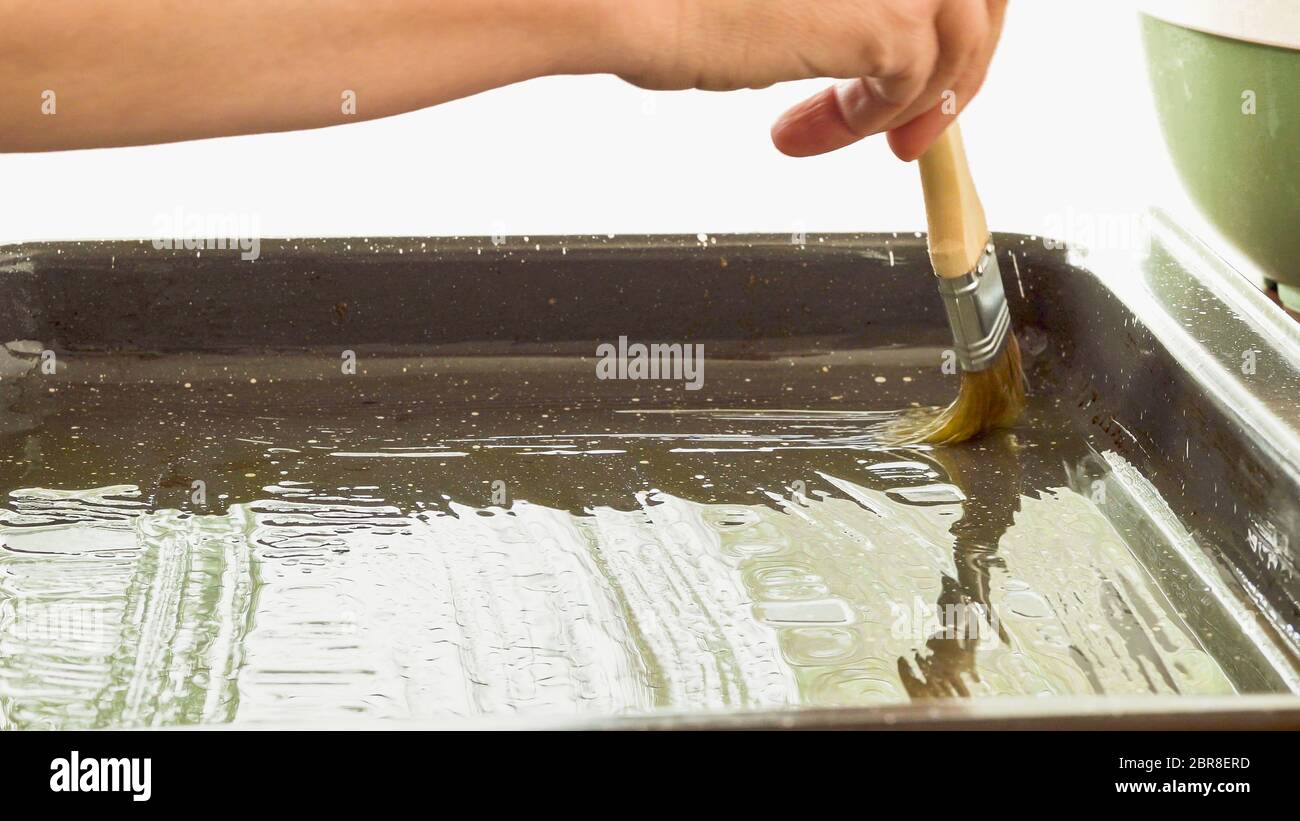 Greasing baking sheet with olive oil. Woman hands, close up on white ...