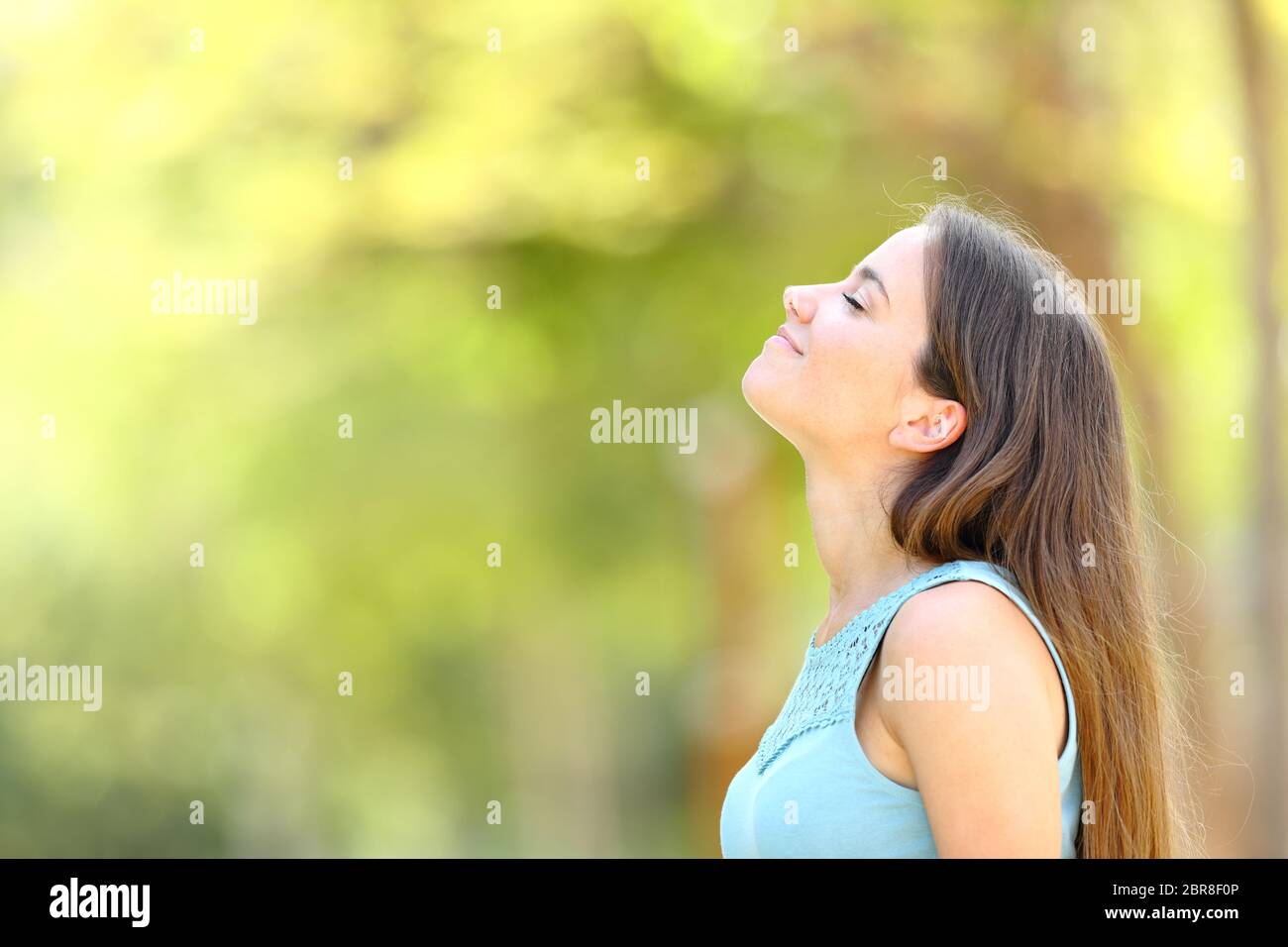 Profile of a woman breathing deeply fresh air in a forest with a warm ...