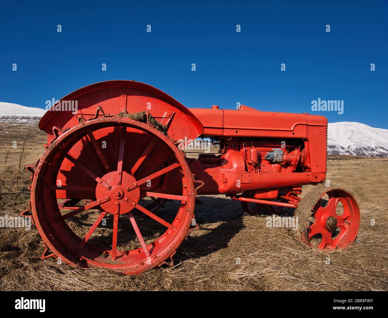 A well preserved oldtimer tractor in the field in front of a mountain ...