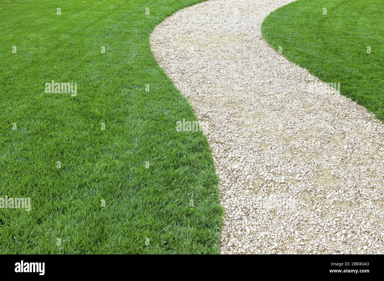 Curved garden stone path with fresh green cultivated lawn in summer ...