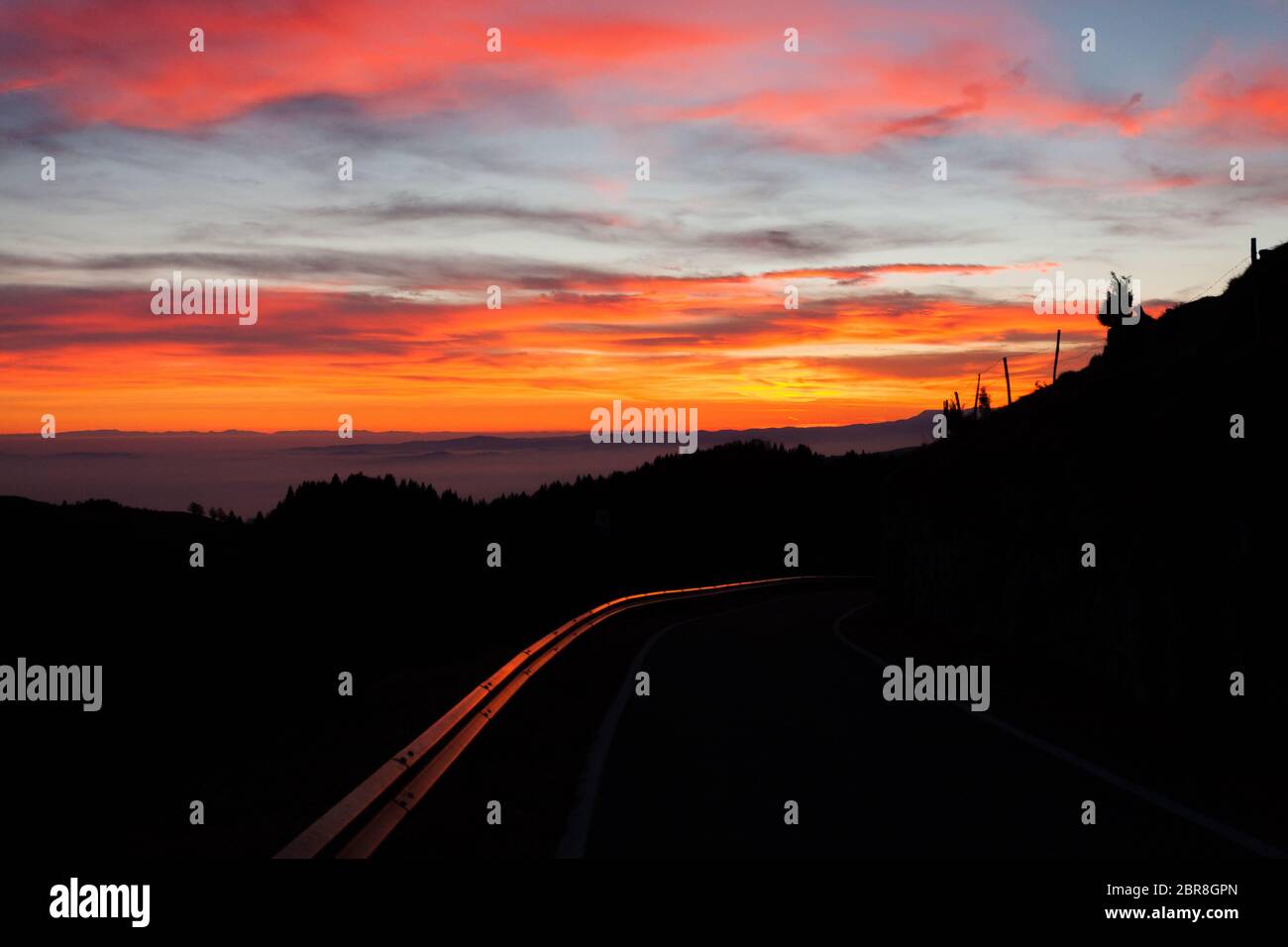 Dramatic red sky with reflections on guard rail road. Darkness ...