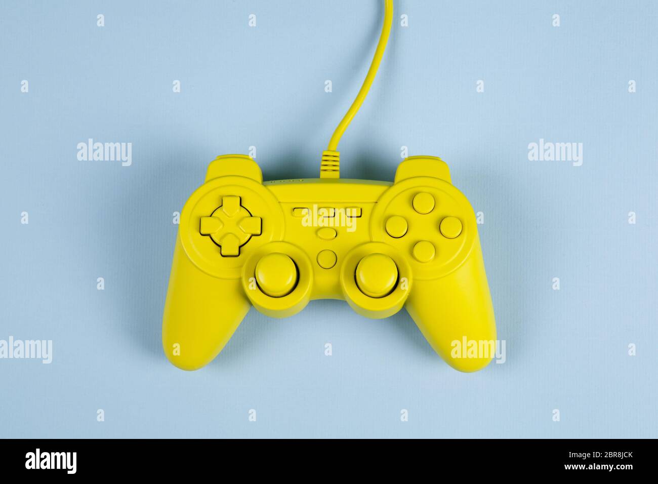 a yellow painted video game controller on a plain blue background ...