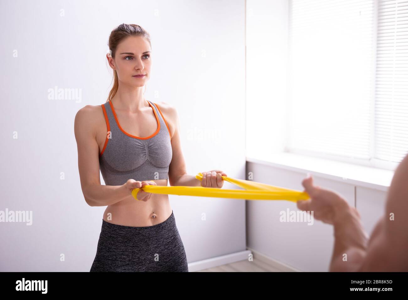 Side View Of Young Woman And Male Gym Trainer Doing Exercise With ...