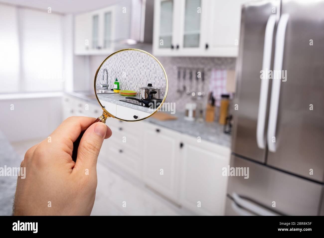 Close-up Of A Man's Hand Holding Magnifying Glass Over The Kitchen In ...