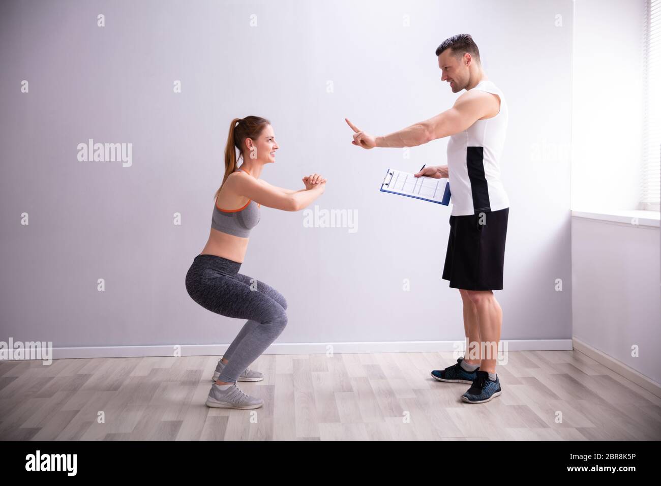 Side View Of Young Sporty Woman Doing Deep Squat Exercise In Front Of ...