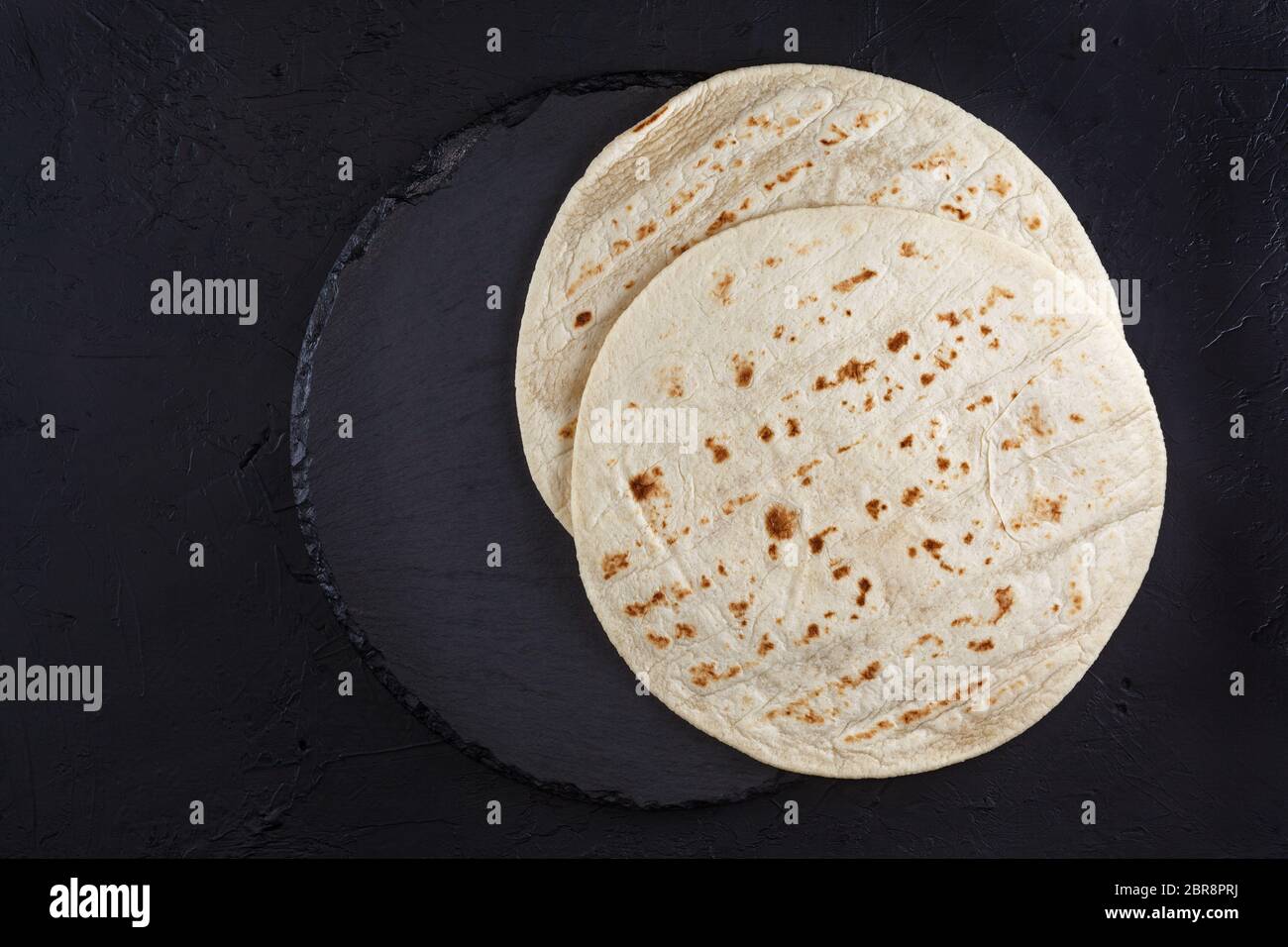 Empty burritos wraps with chicken and vegetables on black slate. Chicken burrito, mexican food ...