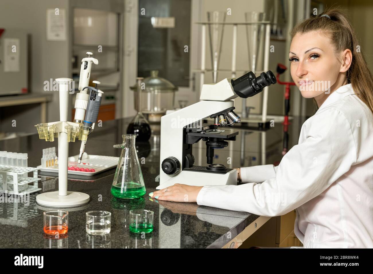 Young, Caucasian white, female laboratory technician in white robe with ...