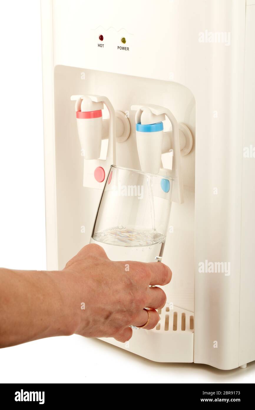 Hand is pouring water into glass from water cooler with big bottle full ...