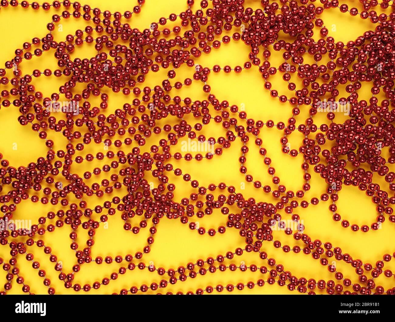 Christmas red garland of round glass balls on a yellow background ...