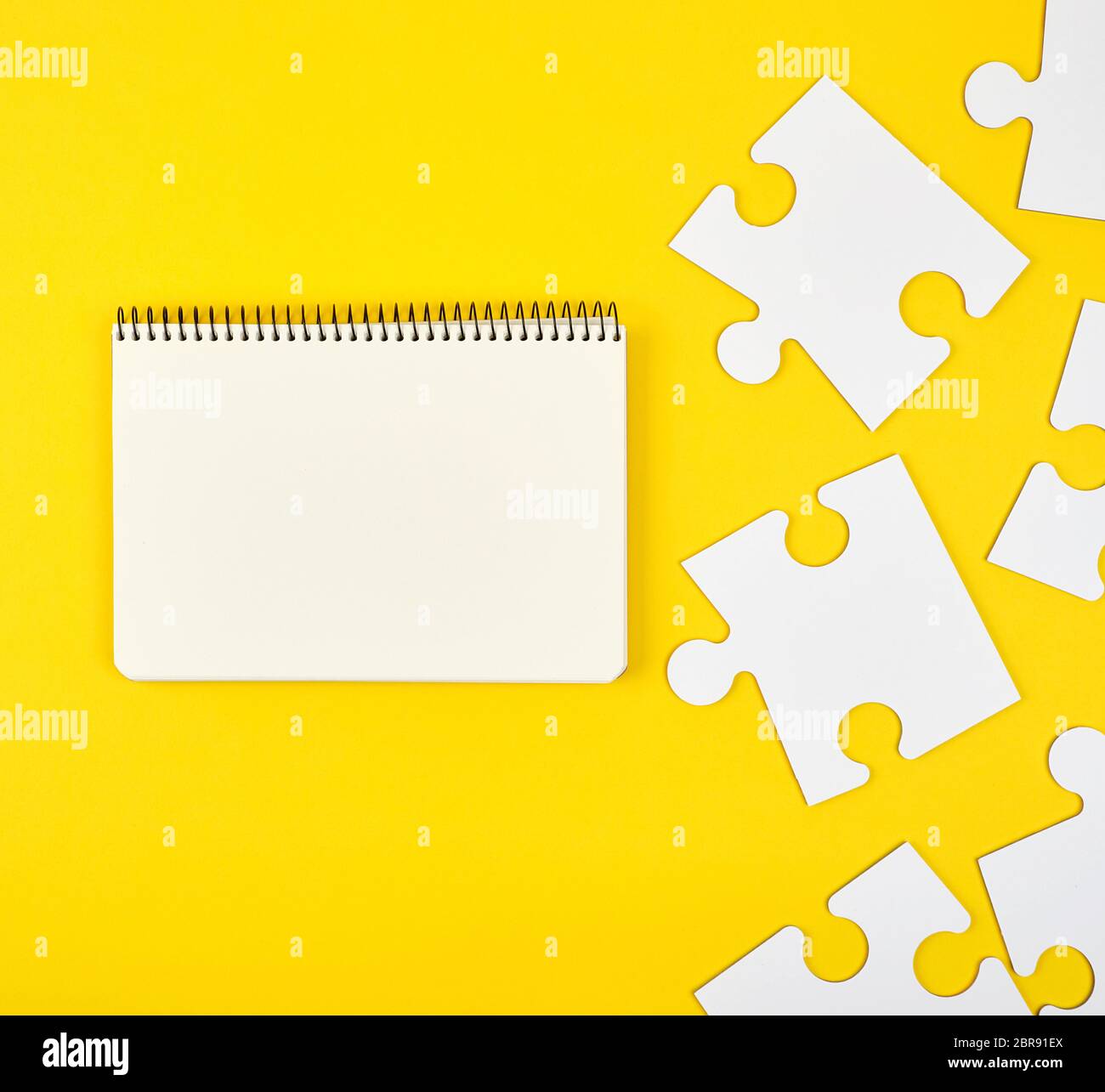 open notebook on a yellow background, next to large white blank puzzles ...