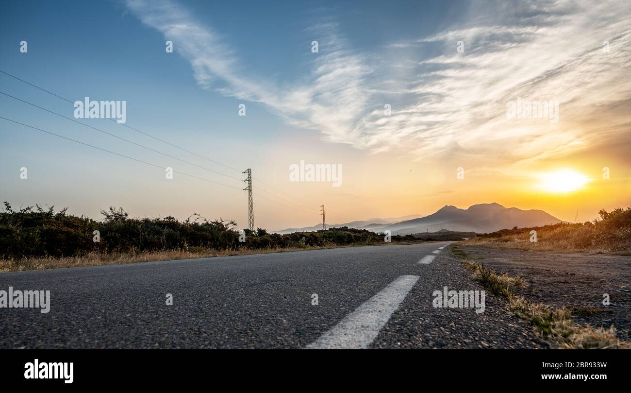 Empty long road on a sunny summer day at bright sunset Stock Photo - Alamy