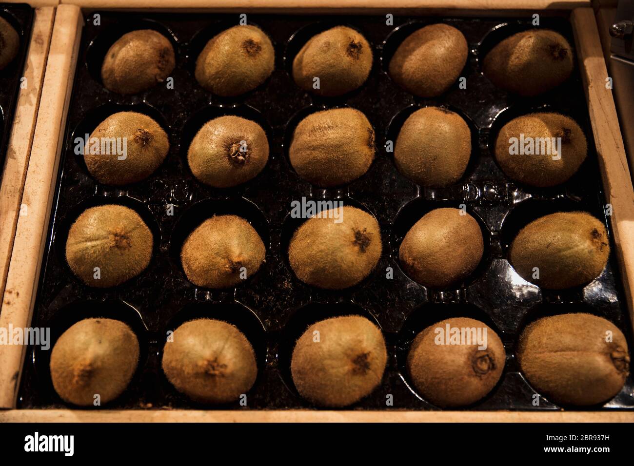 A close-up shot of an abundance of fresh Kiwi on display at a market ...