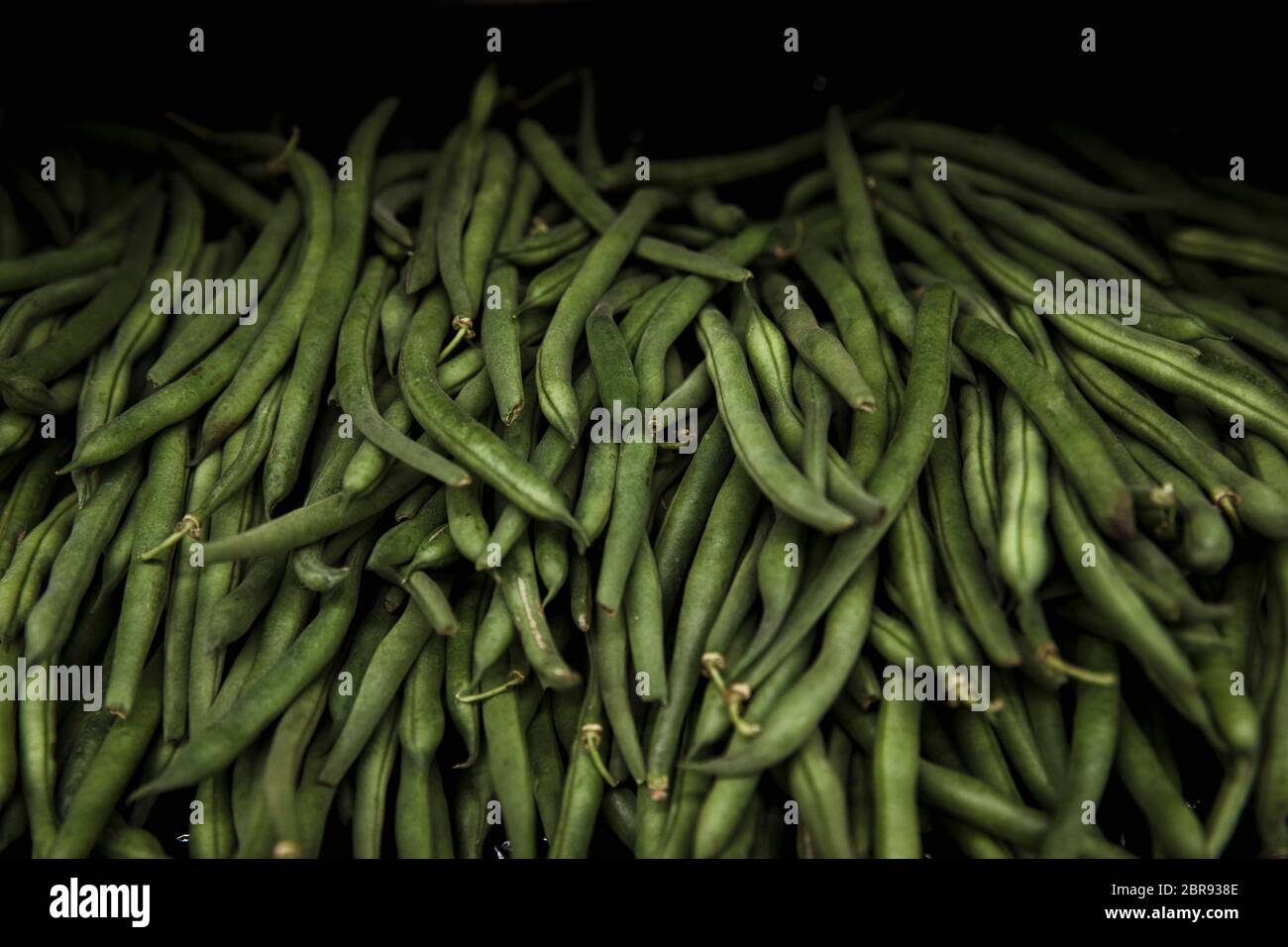 A close-up shot of an abundance of fresh green pea pods on display at a ...