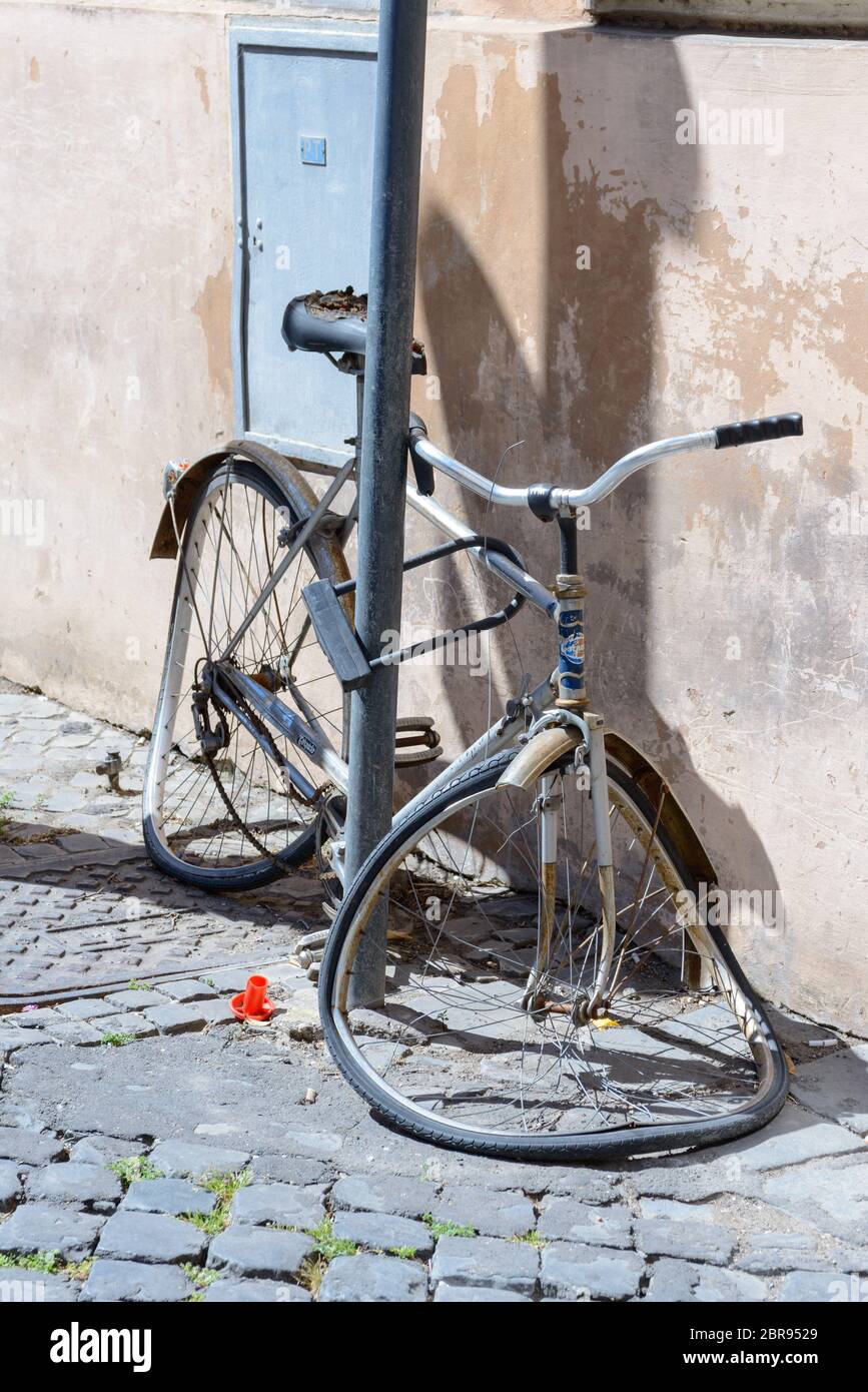 A broken bike tied to a pole in Rome Stock Photo - Alamy