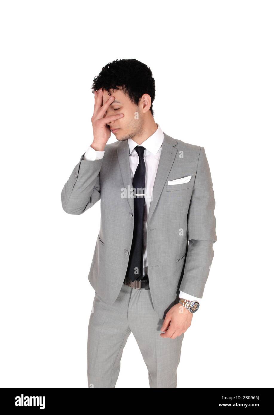 A angry young man standing in a gray suit in the studio with his hand ...
