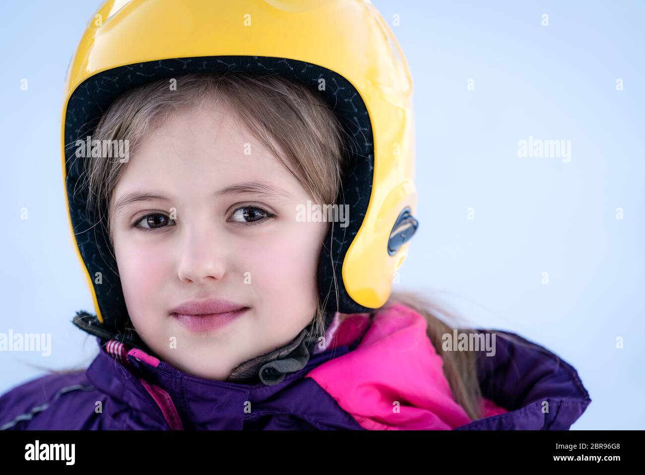 Winter portrait of a little girl wearing yellow ski helmet during ...