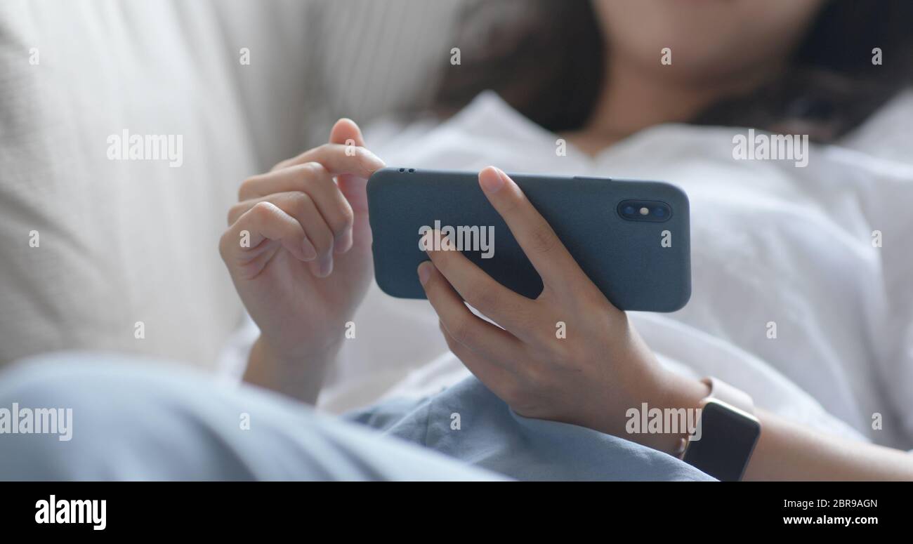 Woman use of smart phone and lying down on sofa Stock Photo - Alamy