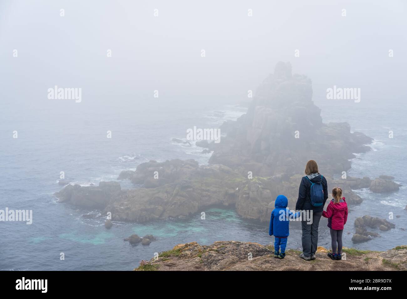 Mother with her children standing on the top of a cliff looking at the ...