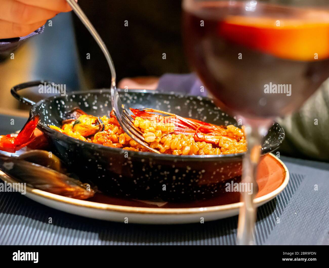 eating Valencian paella in a black pan using a fork. Typical Spanish ...