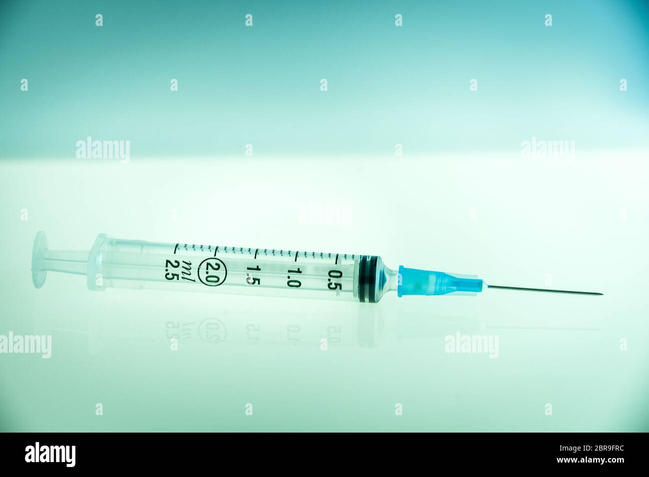 Injection syringe on a clean blue background Stock Photo - Alamy
