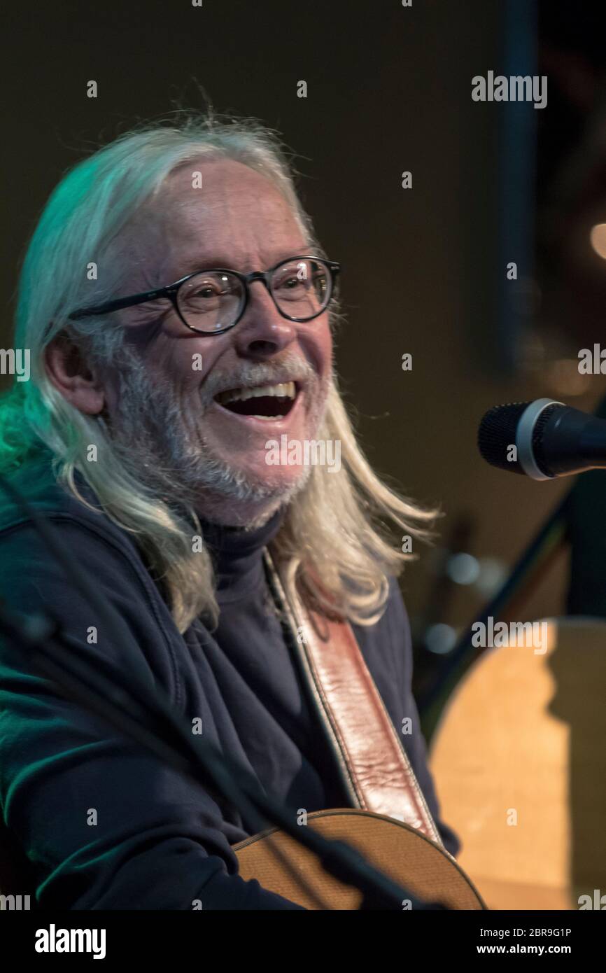 Musicain, with long white hair, laughing while chatting with crowd ...
