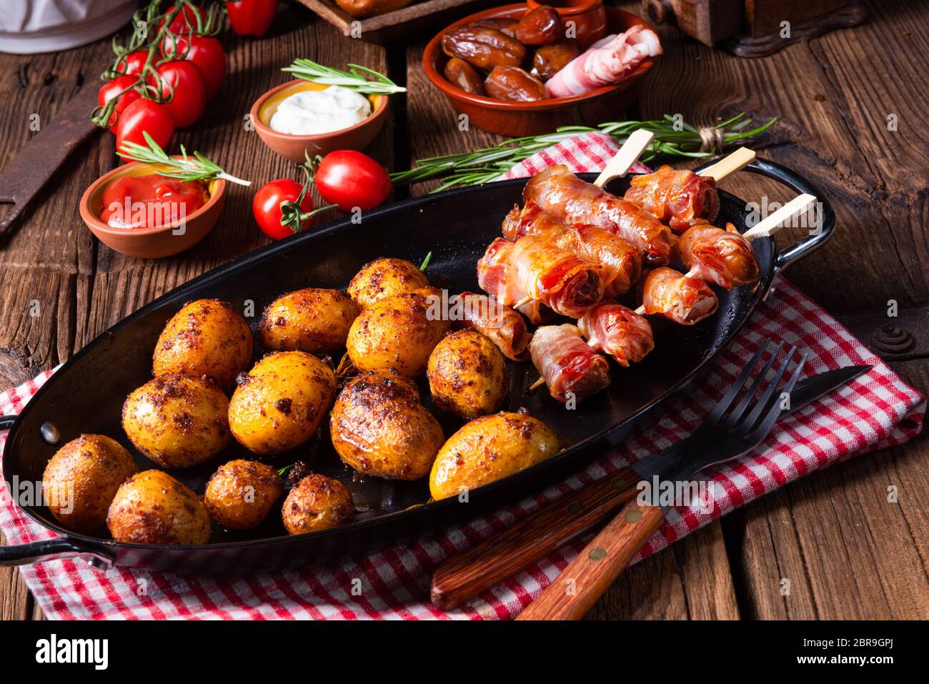 Rustic dates wrapped in bacon and young roasted potato Stock Photo - Alamy