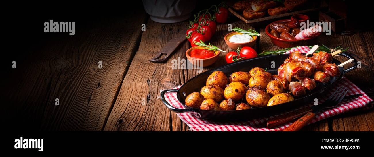 Rustic dates wrapped in bacon and young roasted potato Stock Photo - Alamy