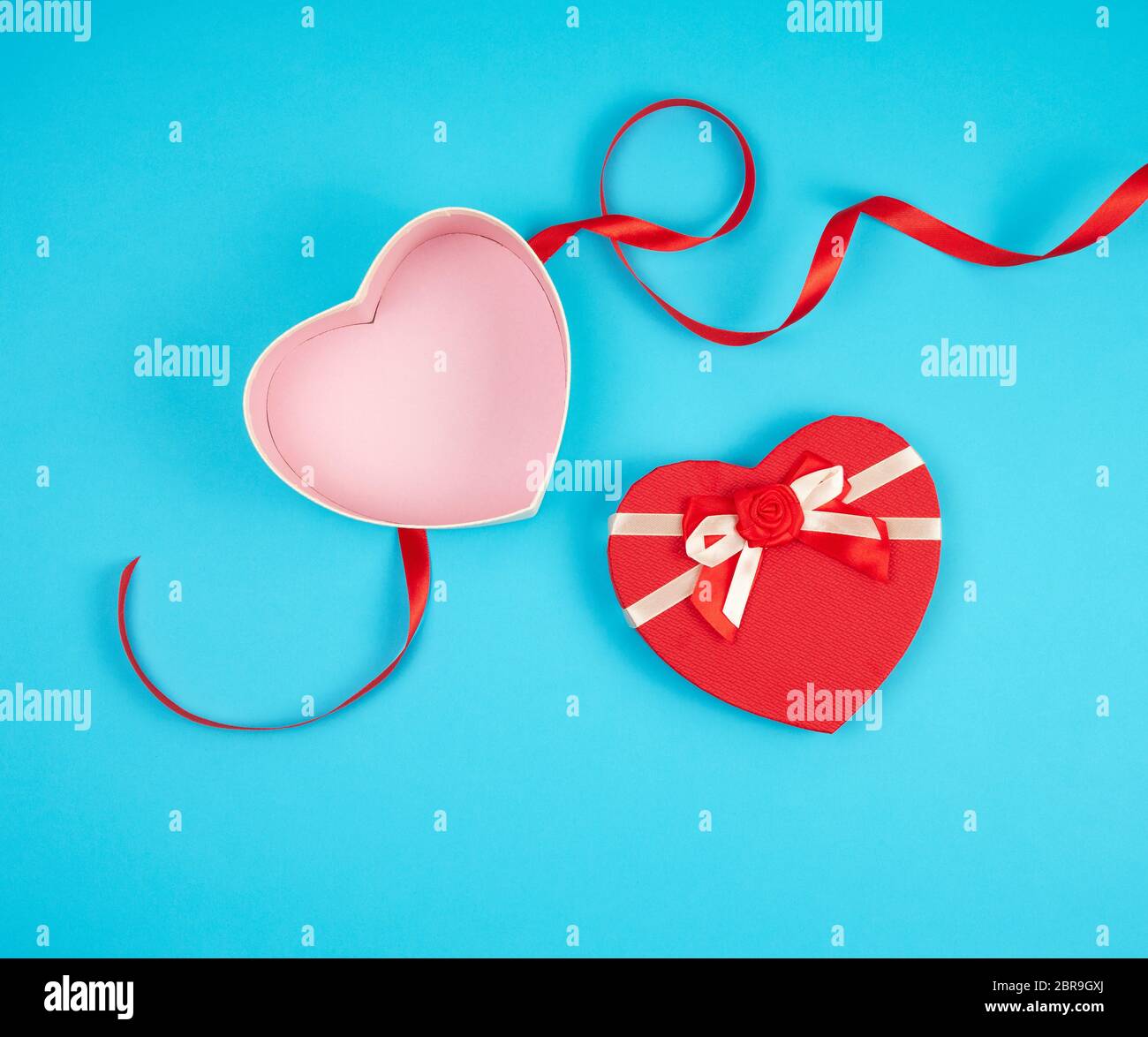 open red heart-shaped gift box with a bow on a blue background, top ...