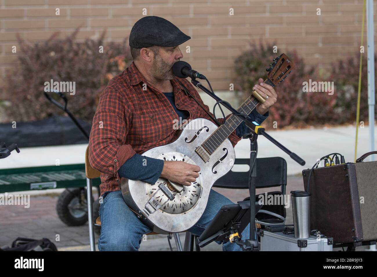 Male folk singer, sitting as he sings and plays resonator guitar, in ...