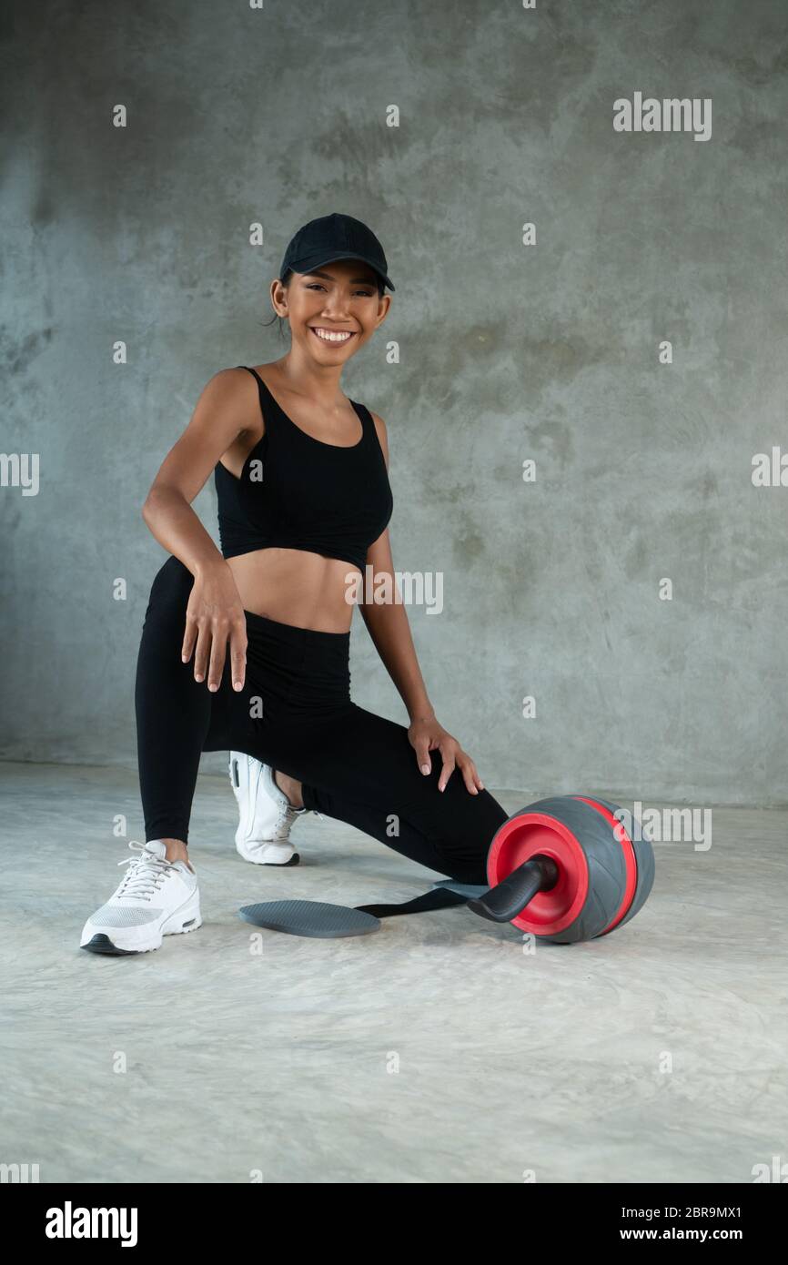 Happy healthy smiling woman working out with fitness roller at the gym ...