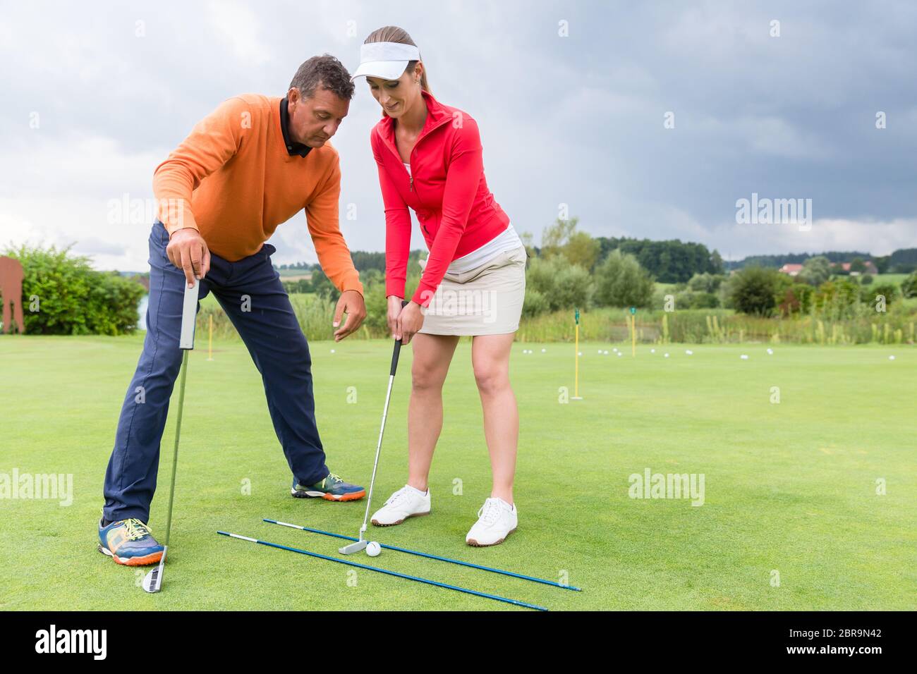 Golf trainer working with female golf player on driving range Stock ...